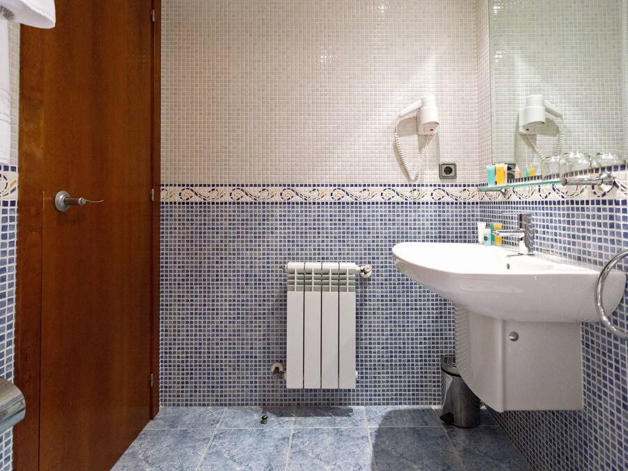 Casa de banho com lavatório branco, espelho e porta-toalhas.