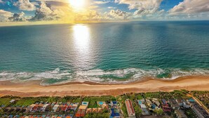 Vista aérea de uma área costeira com praia, oceano e edifícios residenciais.