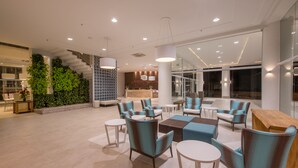 Um lobby moderno com escadaria, área de estar e balcão de recepção.