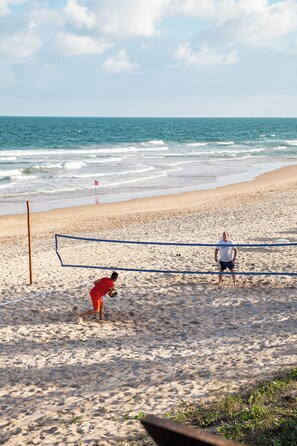 Na praia, espreguiçadeiras, guarda-sóis de praia, voleibol de praia 