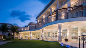 Um hotel com várias andares, fachada curva, área de estar ao ar livre e piscina.