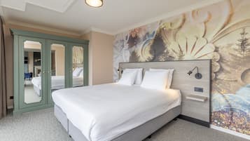 Cama bem arrumada em quarto de hotel, com um espelho grande e um mural na parede.