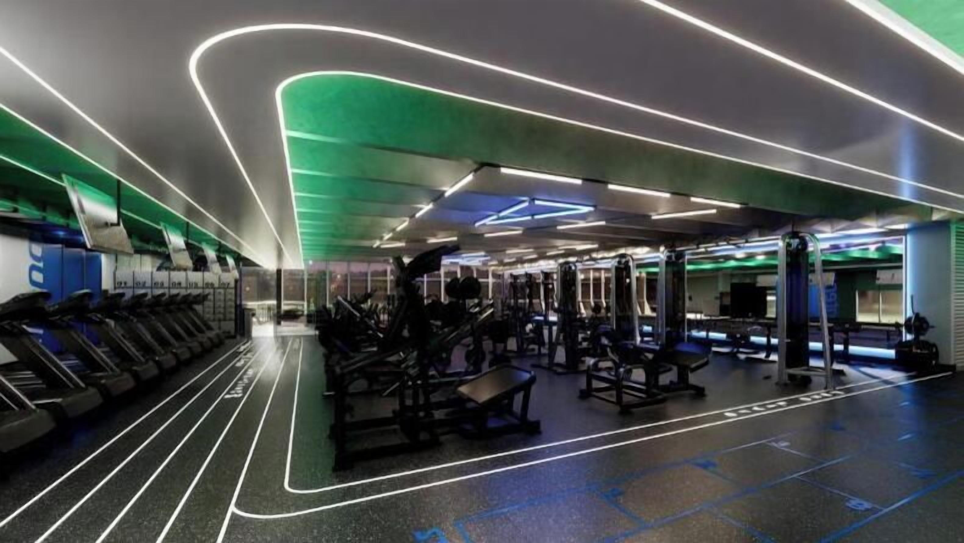 Uma academia com esteiras, máquinas de musculação e espelhos.