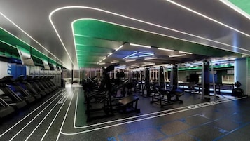 Uma academia com esteiras, máquinas de musculação e espelhos.