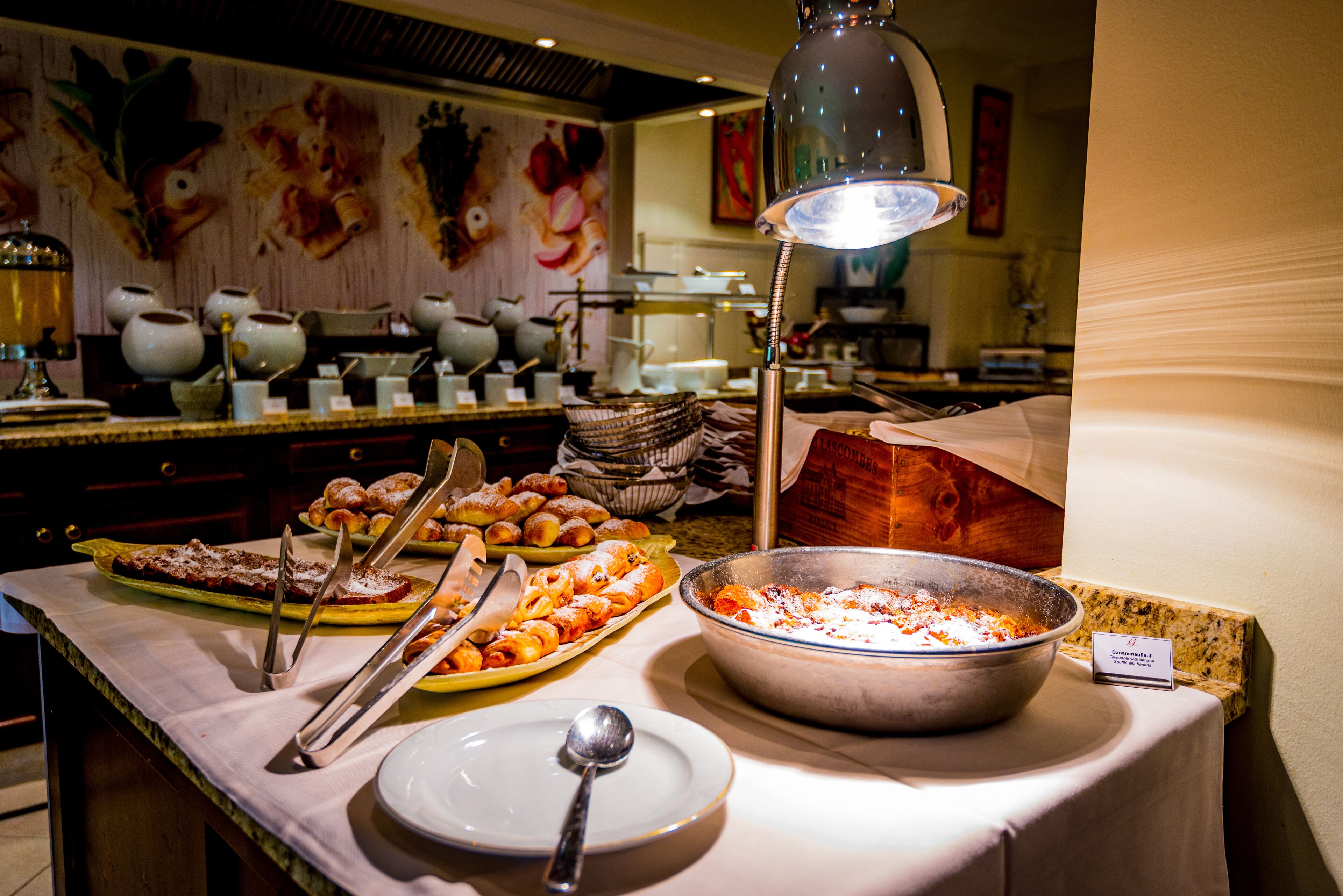 Uma mesa de buffet com diversos pratos, utensílios e uma tigela de massa.