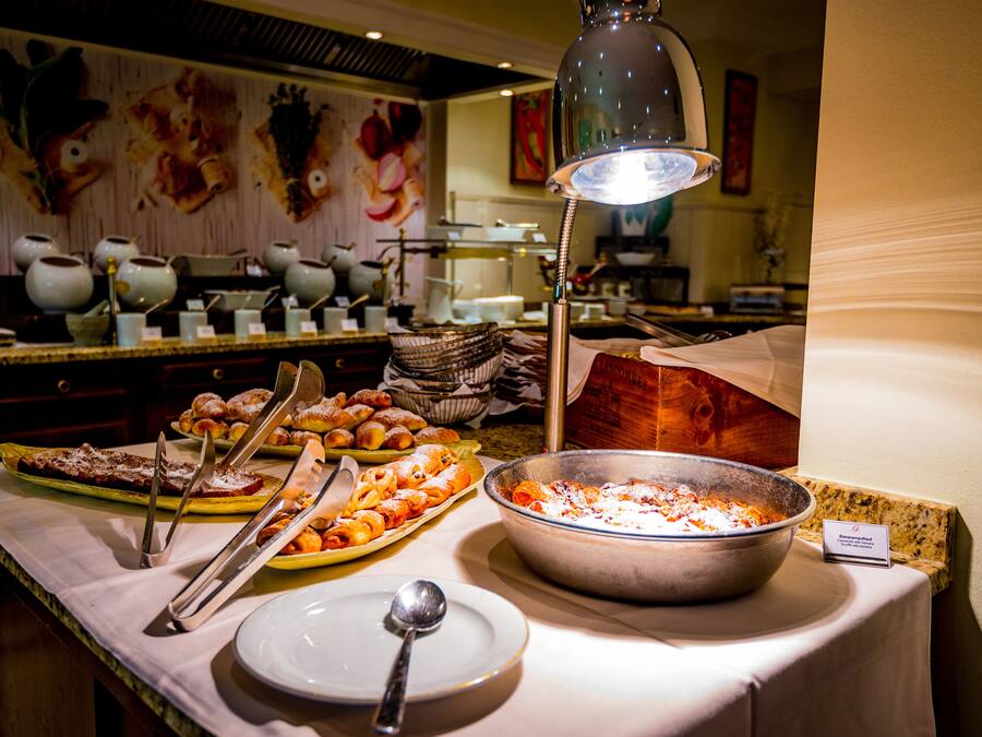 Uma mesa de buffet com diversos pratos, utensílios e uma tigela de massa.