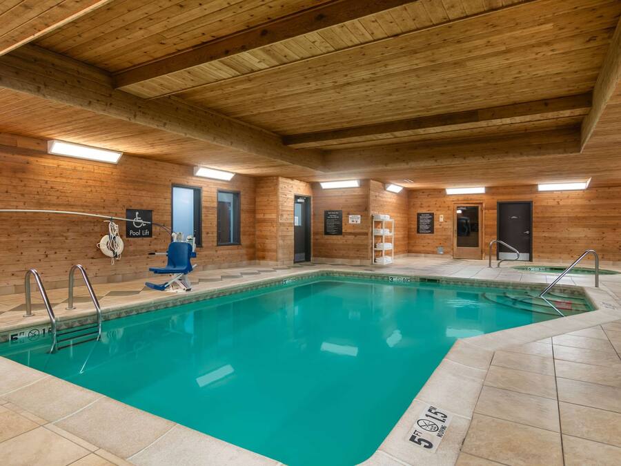 Piscina interna com paredes e teto de madeira, sinalização clara e piso revestido de azulejos.