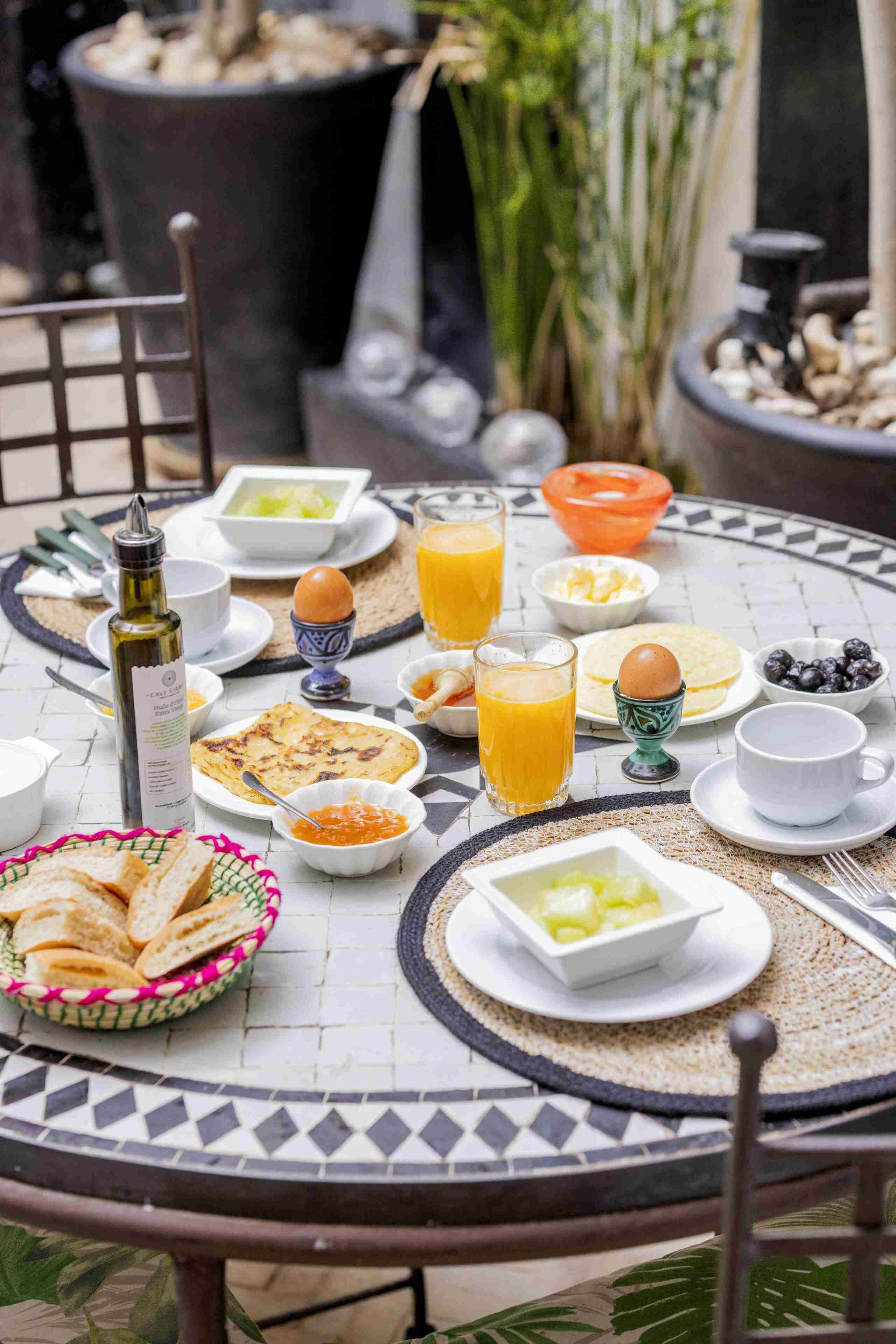 Mesa redonda com itens de café da manhã, incluindo ovos, torradas e suco de laranja.