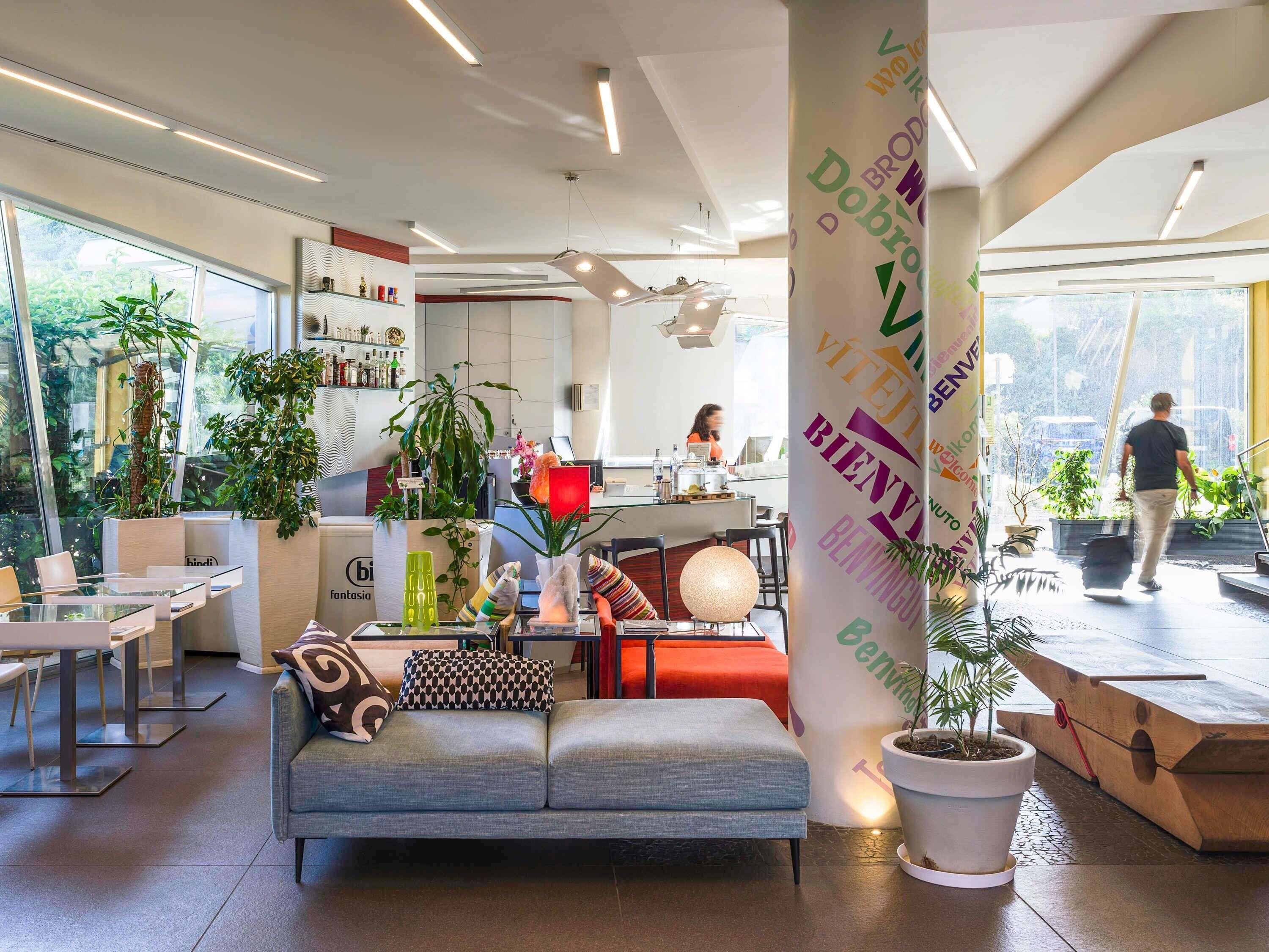 Um interior moderno com sofá, mesas e plantas em vasos.