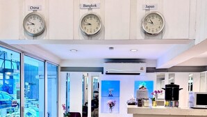 Uma área de recepção moderna com relógios indicando 'China', 'Bangkok' e 'Japão'.