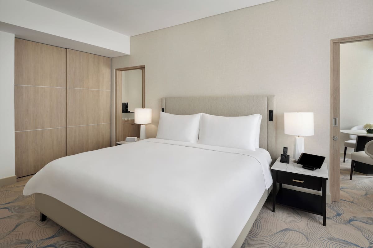 Quarto de hotel com uma cama grande, mesas de cabeceira, uma escrivaninha e um espelho.
