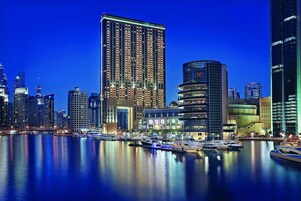 Horizonte urbano com edifícios modernos e arranha-céus, e uma marina com barcos.