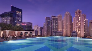 Uma área de piscina moderna de hotel, com um horizonte urbano ao fundo.