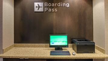 Balcão com computador, teclado e rato, e um aviso acima com a inscrição 'Boarding Pass'.
