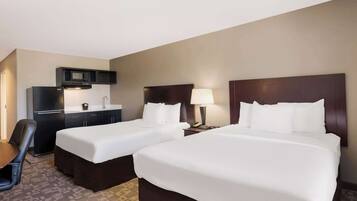 Quarto de hotel com duas camas, uma escrivaninha, micro-ondas e pia.