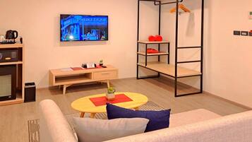 Uma sala de estar moderna com sofá, mesa de centro, televisão e uma pequena estante.