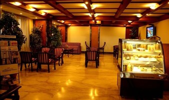 Um hall de hotel com sofás listrados, uma vitrine de vidro e piso de madeira.