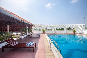 Uma área de piscina no terraço com espreguiçadeiras, piscina e uma estrutura de pérgola.