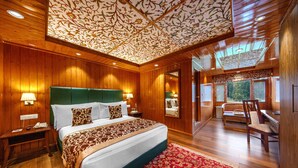 Quarto amplo com cama grande, paredes de madeira e teto estampado.