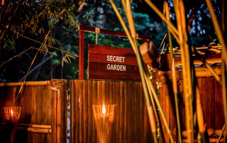 Um portão de madeira com uma placa que diz 'SECRET GARDEN'.