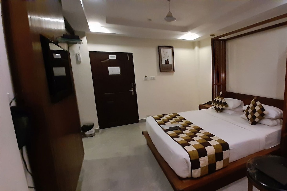 Quarto de hotel com cama, mesa de cabeceira e porta.