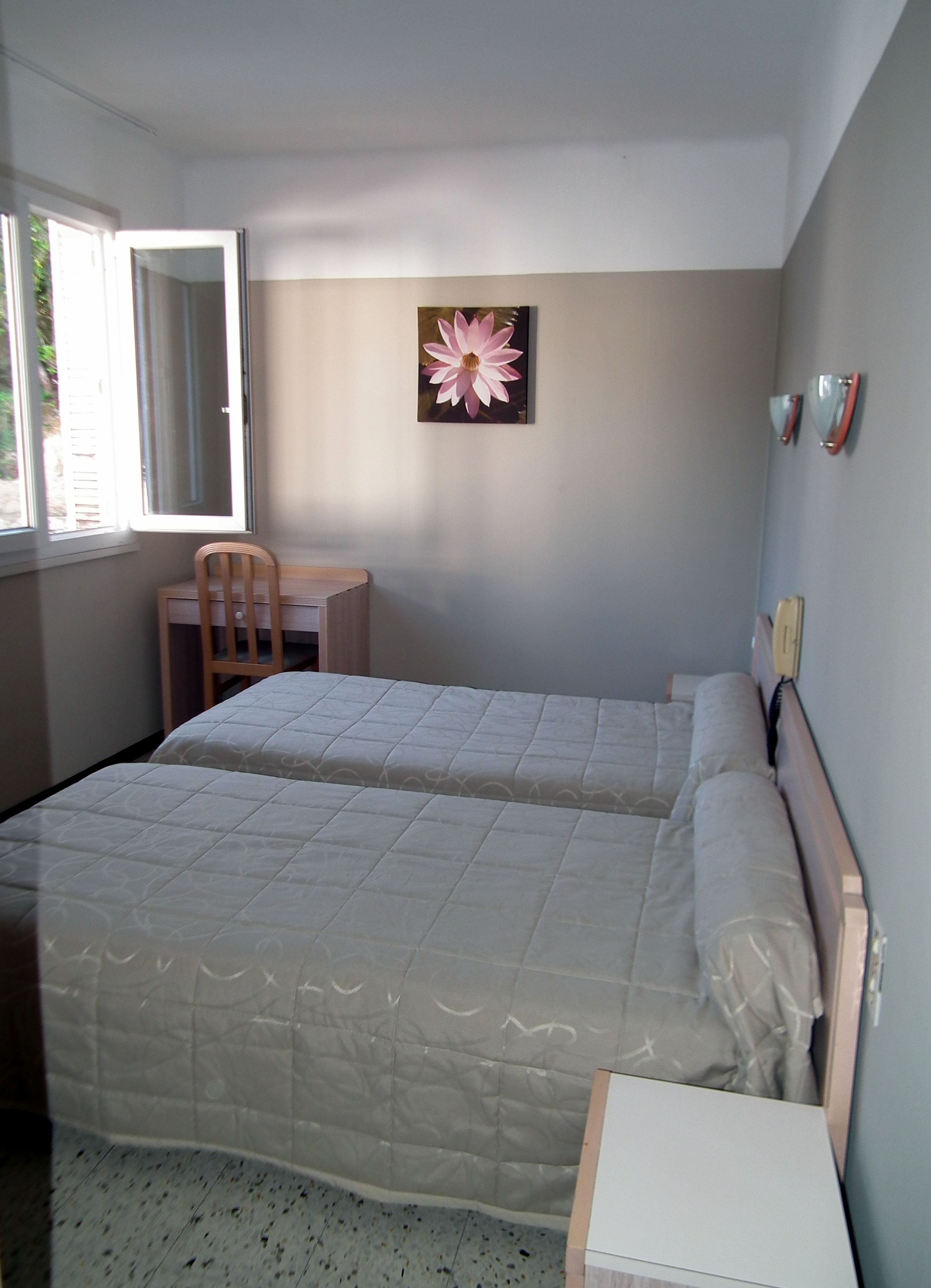 Quarto com uma cama de casal, uma escrivaninha e uma cadeira.