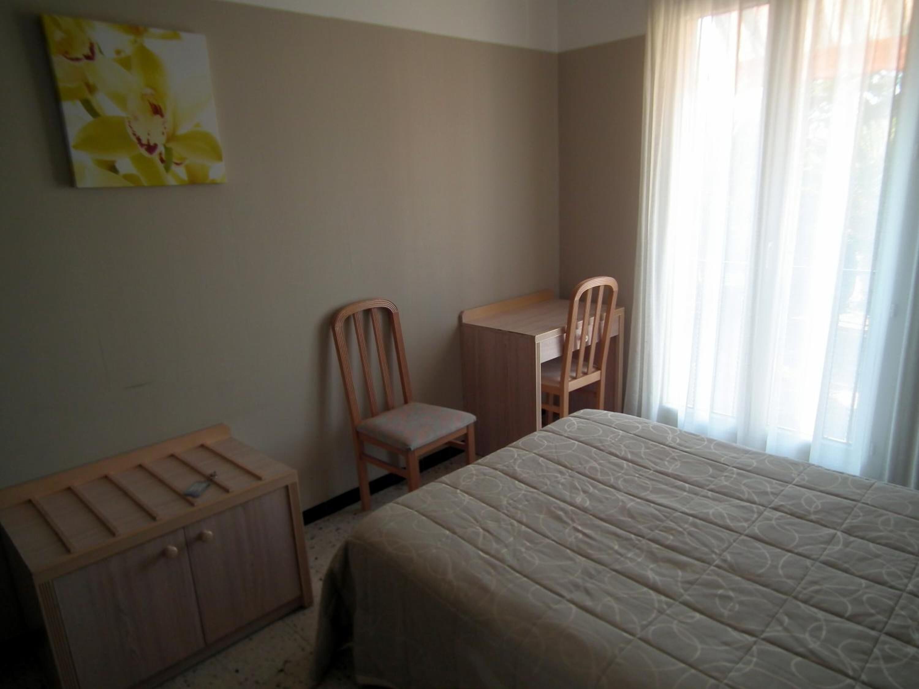 Um quarto com uma cama, uma escrivaninha e uma cadeira.