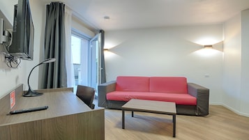 Uma sala de estar moderna com um sofá vermelho, uma mesa de centro de madeira, uma escrivaninha com um controle remoto e uma TV fixada na parede.