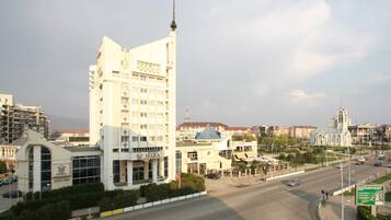 Um hotel moderno com uma torre imponente e uma igreja ao fundo.