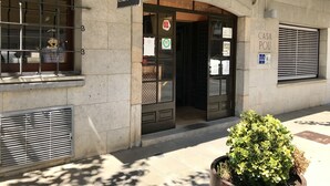 Entrada de um prédio com uma placa indicando "CASA POU" e um vaso de planta em frente.