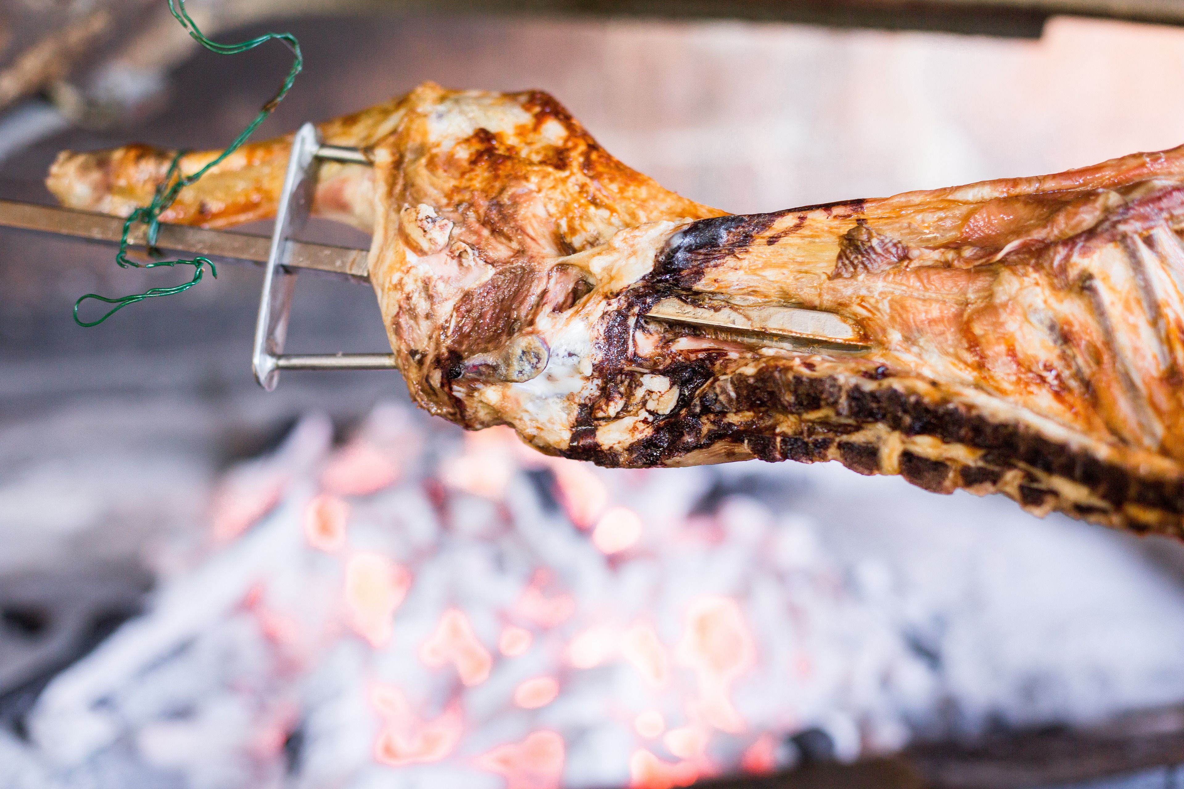 Um frango inteiro assado espetado sobre o fogo.