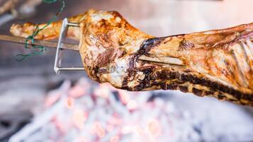 Um frango inteiro assado espetado sobre o fogo.