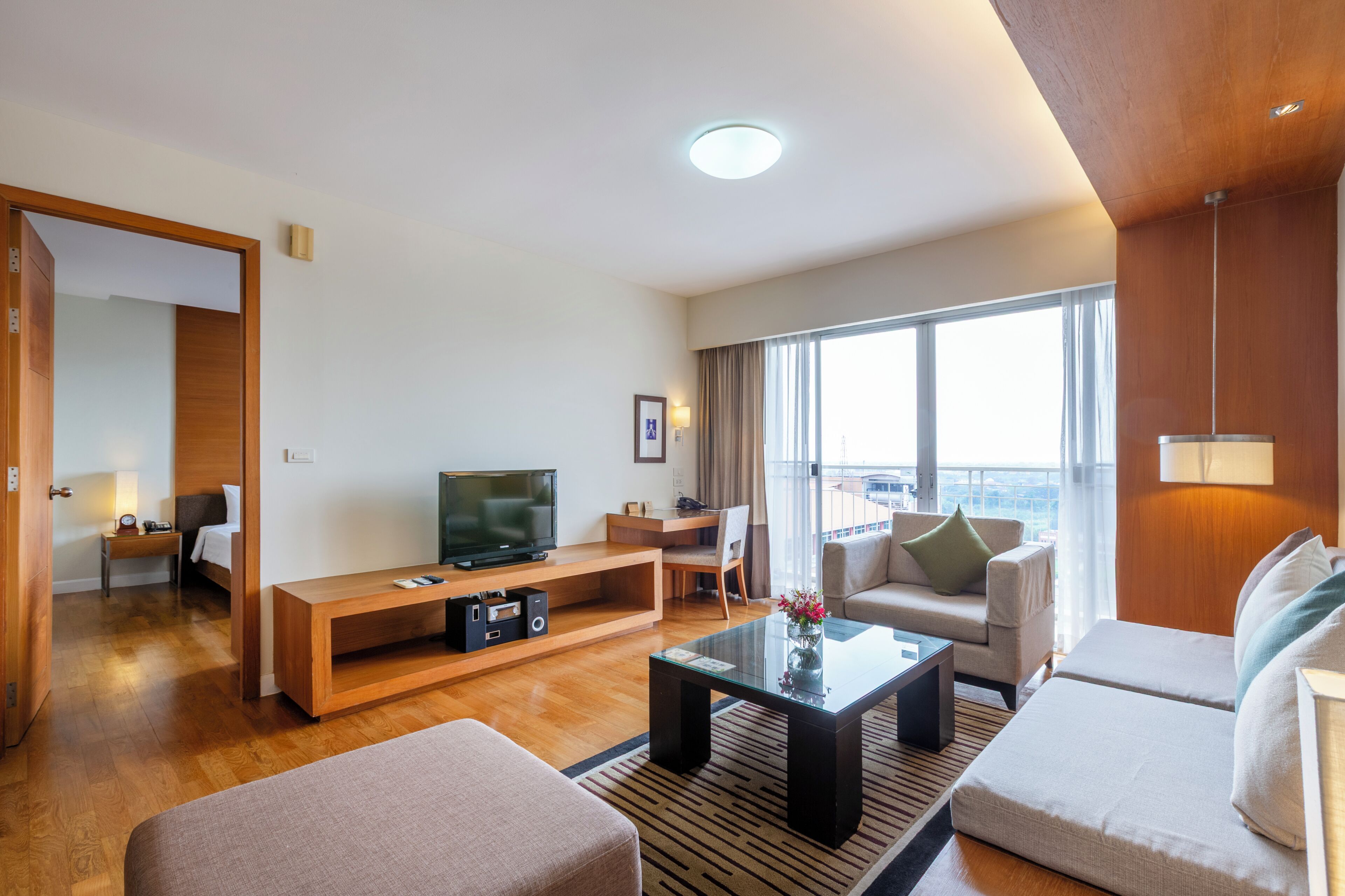 Quarto de hotel moderno com televisão, sofá e área de refeições.