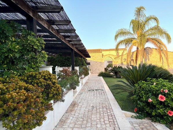 Uma rua de paralelepípedos que leva a um edifício com telhado de azulejos e parede de pedra.