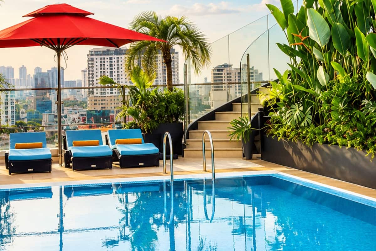 Piscina no terraço com espreguiçadeiras e um guarda-sol vermelho, cercada por vegetação e com vista para a cidade.