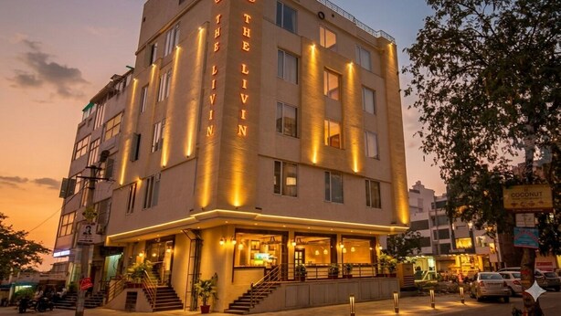 Um hotel de vários andares com letreiros iluminados, um restaurante no térreo e uma escadaria que leva à entrada.