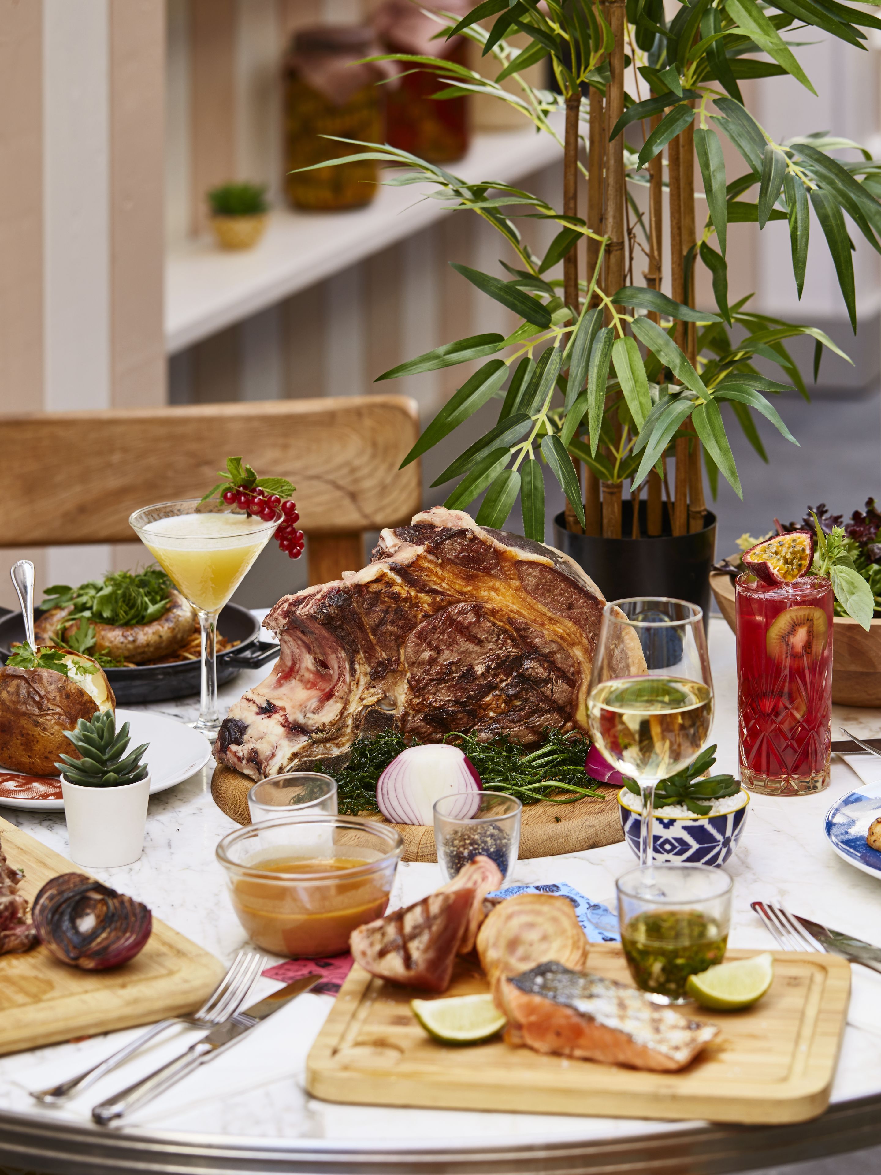 Uma mesa posta com um pernil assado, acompanhamentos diversos e bebidas.
