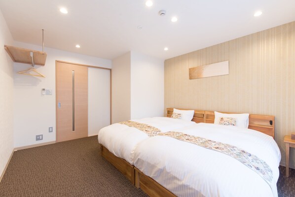 Quarto de hotel com uma cama grande, cabeceira de madeira, um guarda-roupa de madeira, uma obra de arte na parede e uma pequena mesa de cabeceira.