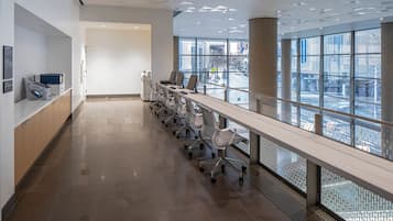 Uma sala de conferências com uma mesa comprida, cadeiras e vista da cidade por grandes janelas.