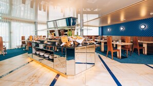 Uma sala de jantar moderna com buffet, divisórias de vidro e uma parede azul destacada.