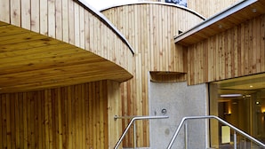 Um edifício de madeira com área de piscina, incluindo escadaria de metal que leva a uma porta de vidro.