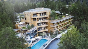 Um hotel com vários andares e piscina, rodeado por árvores.