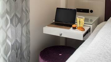 Um espaço de trabalho bem organizado com um laptop, uma chávena e um muffin sobre uma mesa de cabeceira.