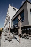 An outdoor seating area with tables and chairs, umbrellas, and a building with a sign reading "GUTLANDS".