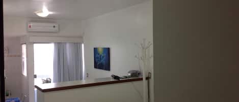 Quarto de hotel com cama, escrivaninha, cadeira, porta-casacos e um quadro na parede.