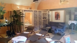 Uma sala iluminada pelo sol, com um sofá, poltronas, uma mesinha e um vaso de planta.