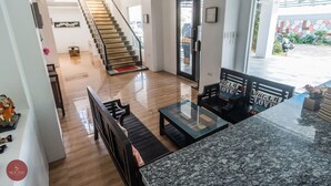 Uma sala de estar espaçosa com escada de madeira, mesa de centro de vidro e bancada de cozinha.