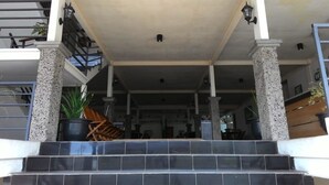 Escadaria que leva a uma entrada coberta, com piso de azulejos e colunas.