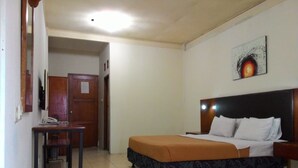 Quarto de hotel com uma cama, uma escrivaninha e uma cadeira.