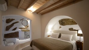 Quarto com uma cama grande, uma banheira integrada e decoração de parede de pedra.
